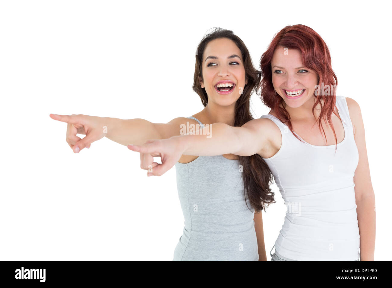 Two cheerful female friends pointing away Stock Photo - Alamy