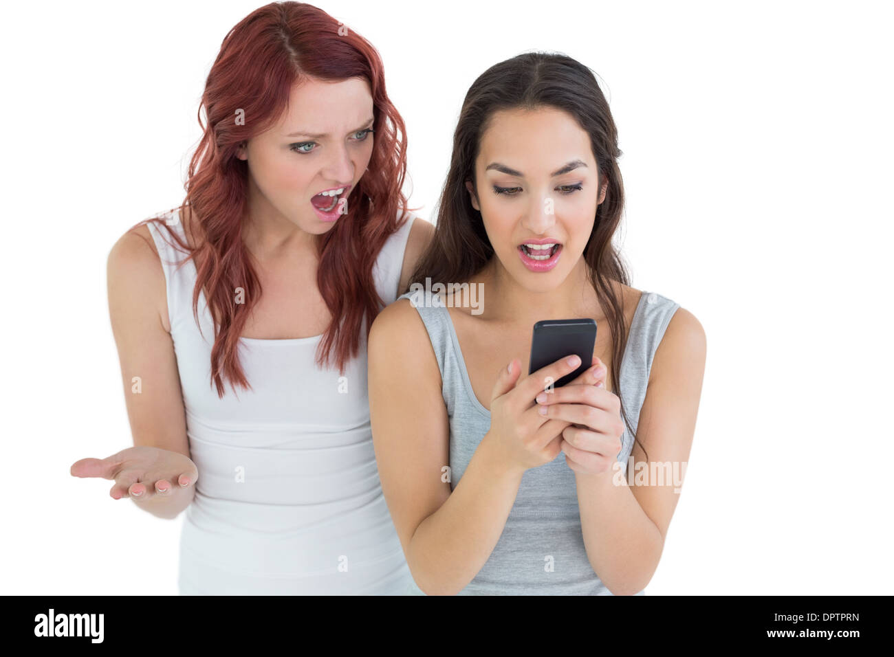 Shocked female friends looking at mobile phone Stock Photo - Alamy
