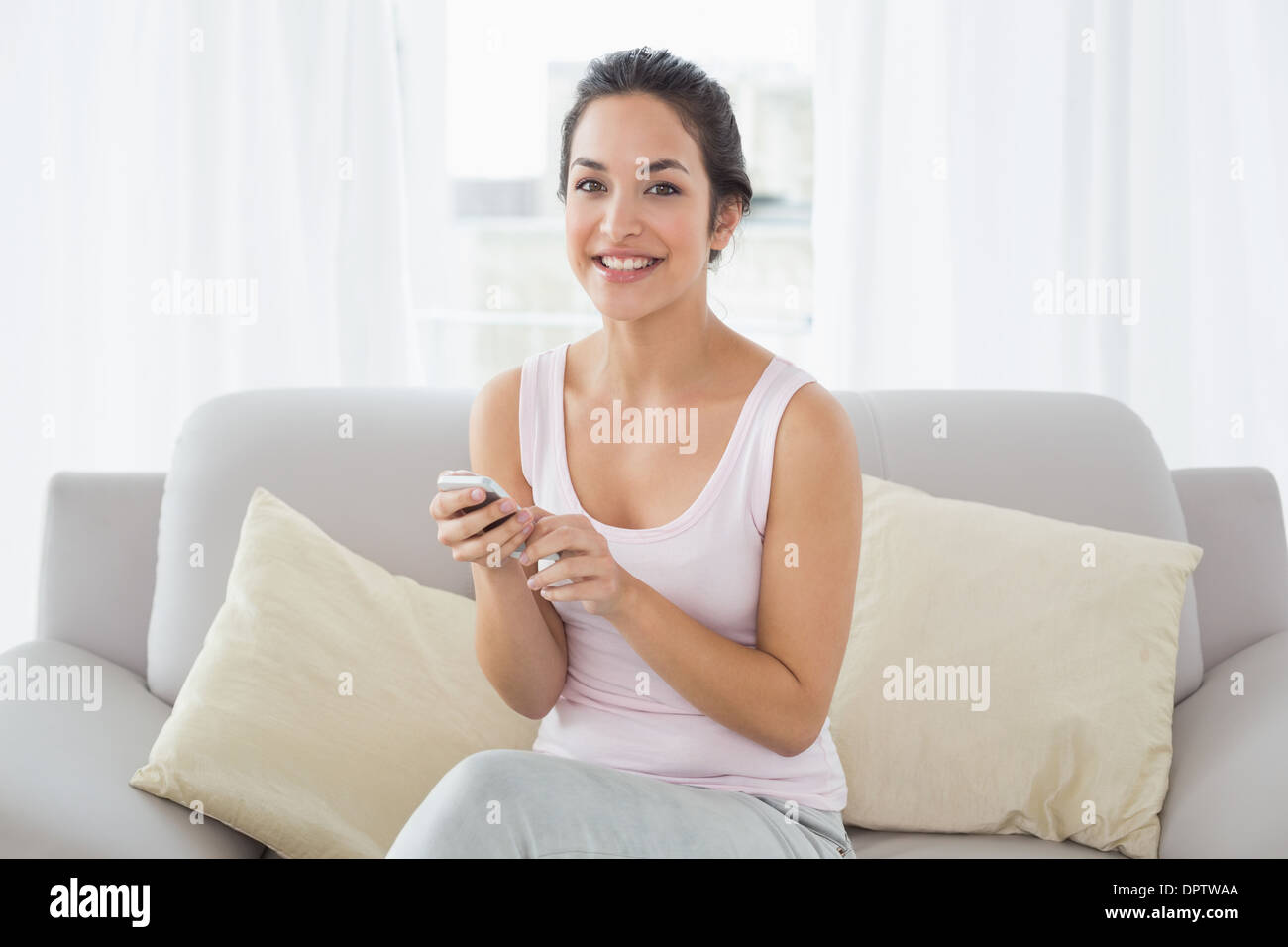 Portrait of a smiling woman text messaging on sofa Stock Photo - Alamy