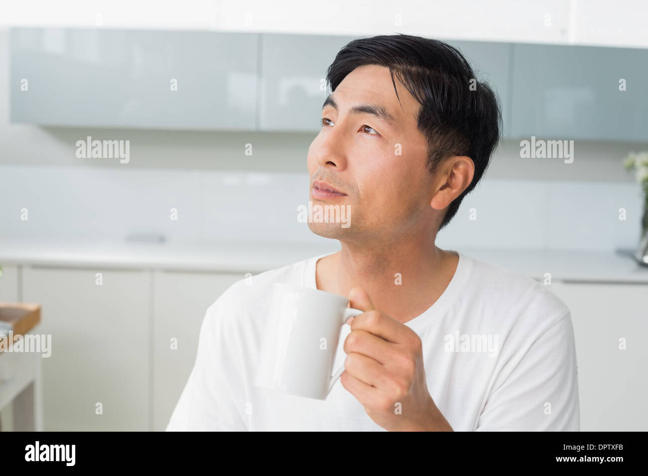 Content man drinking coffee as he looks away in kitchen Stock Photo - Alamy