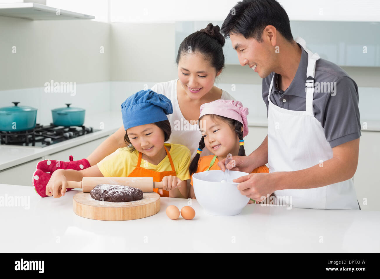 Happy family of four preparing cookies in kitchen Stock Photo - Alamy