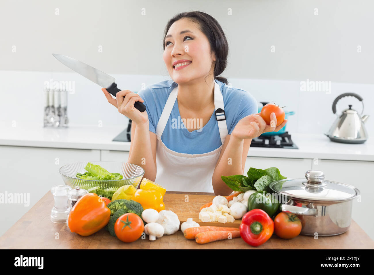 Thoughtful woman chopping vegetables in kitchen Stock Photo - Alamy