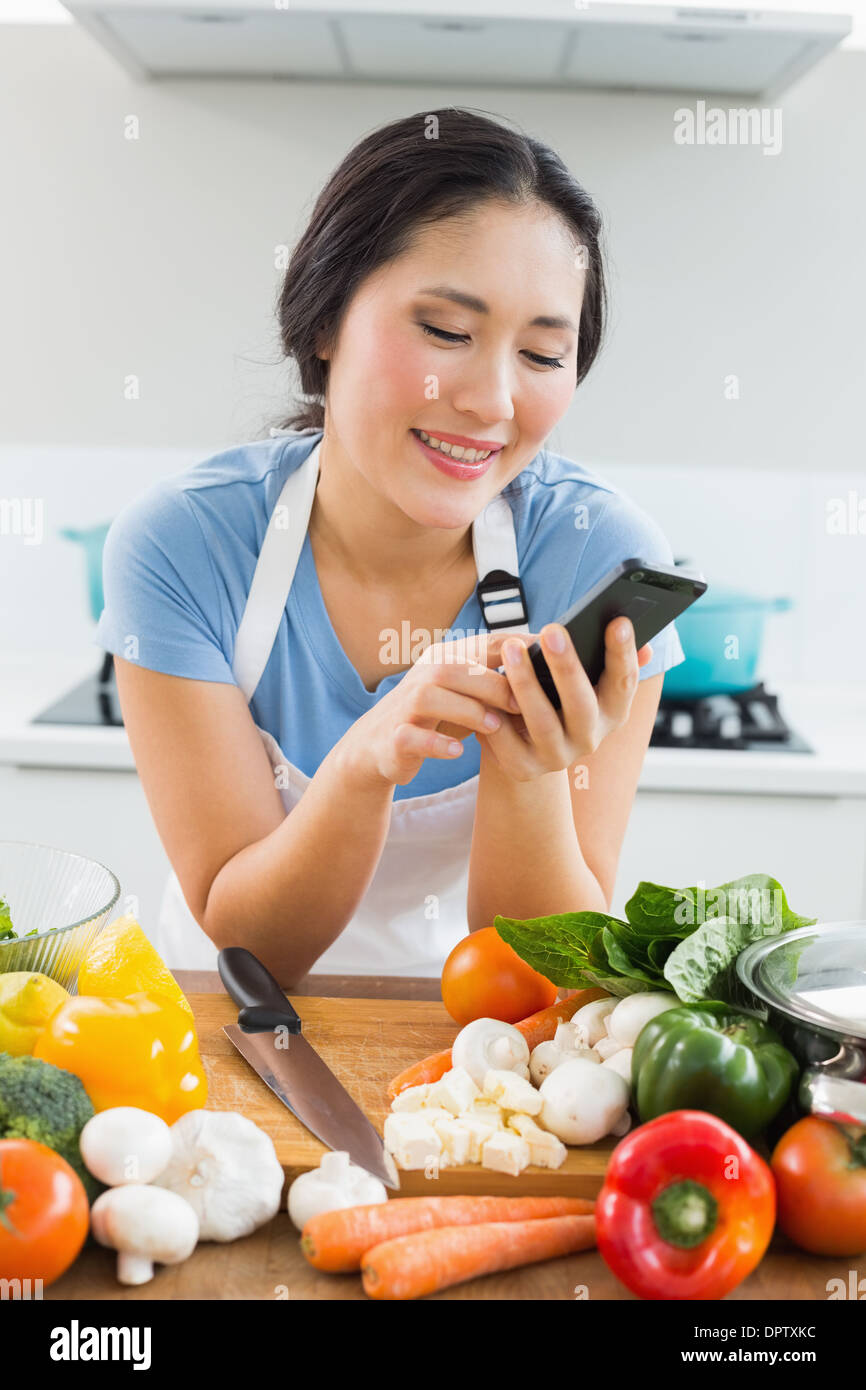 Woman text messaging in front of vegetables in kitchen Stock Photo - Alamy