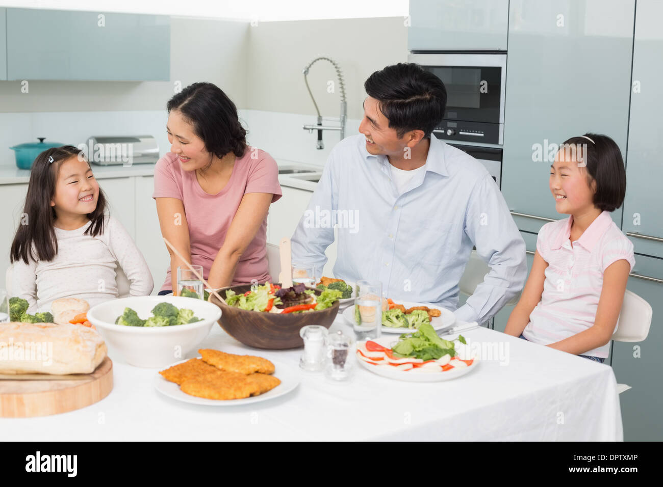 Family of four enjoying healthy meal in kitchen Stock Photo - Alamy