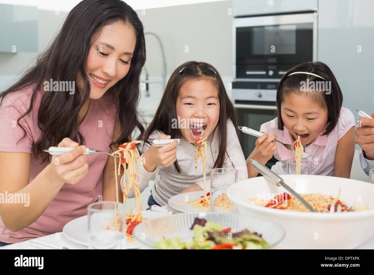 Woman with kids enjoying spaghetti lunch in kitchen Stock Photo - Alamy