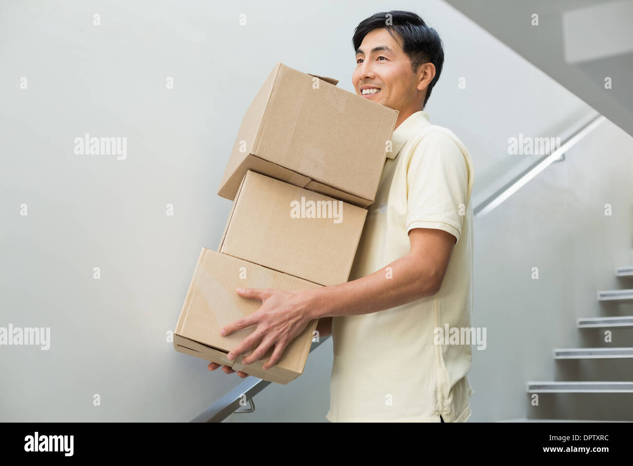 Young man carrying boxes against staircase Stock Photo - Alamy