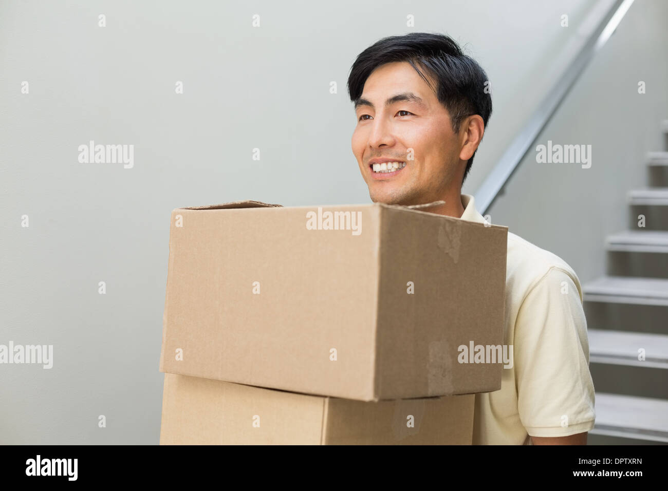 Smiling young man carrying boxes Stock Photo - Alamy