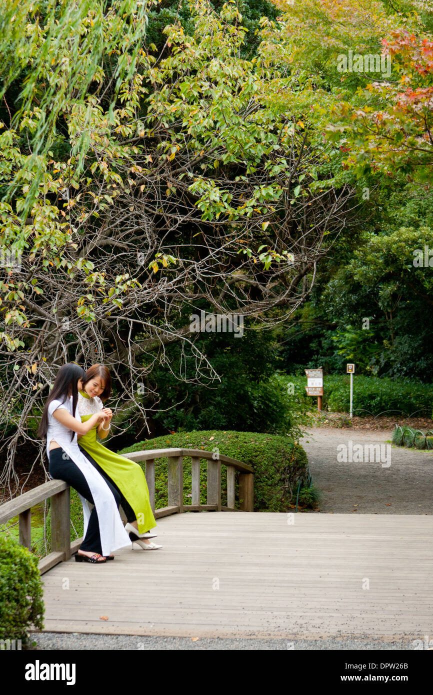Two young women sitting on the edge of a arch bridge Stock Photo - Alamy