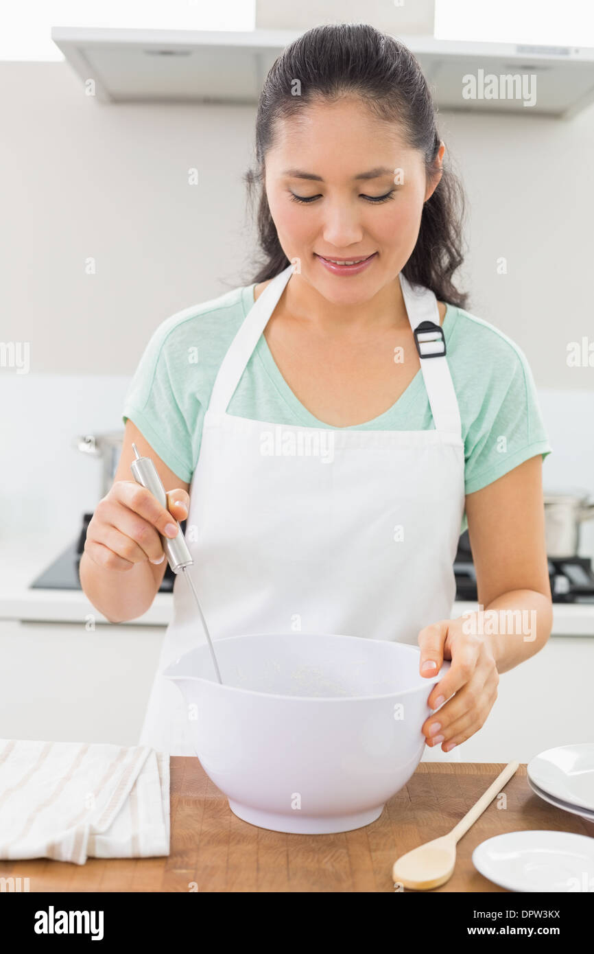 Smiling young woman preparing food in kitchen Stock Photo - Alamy