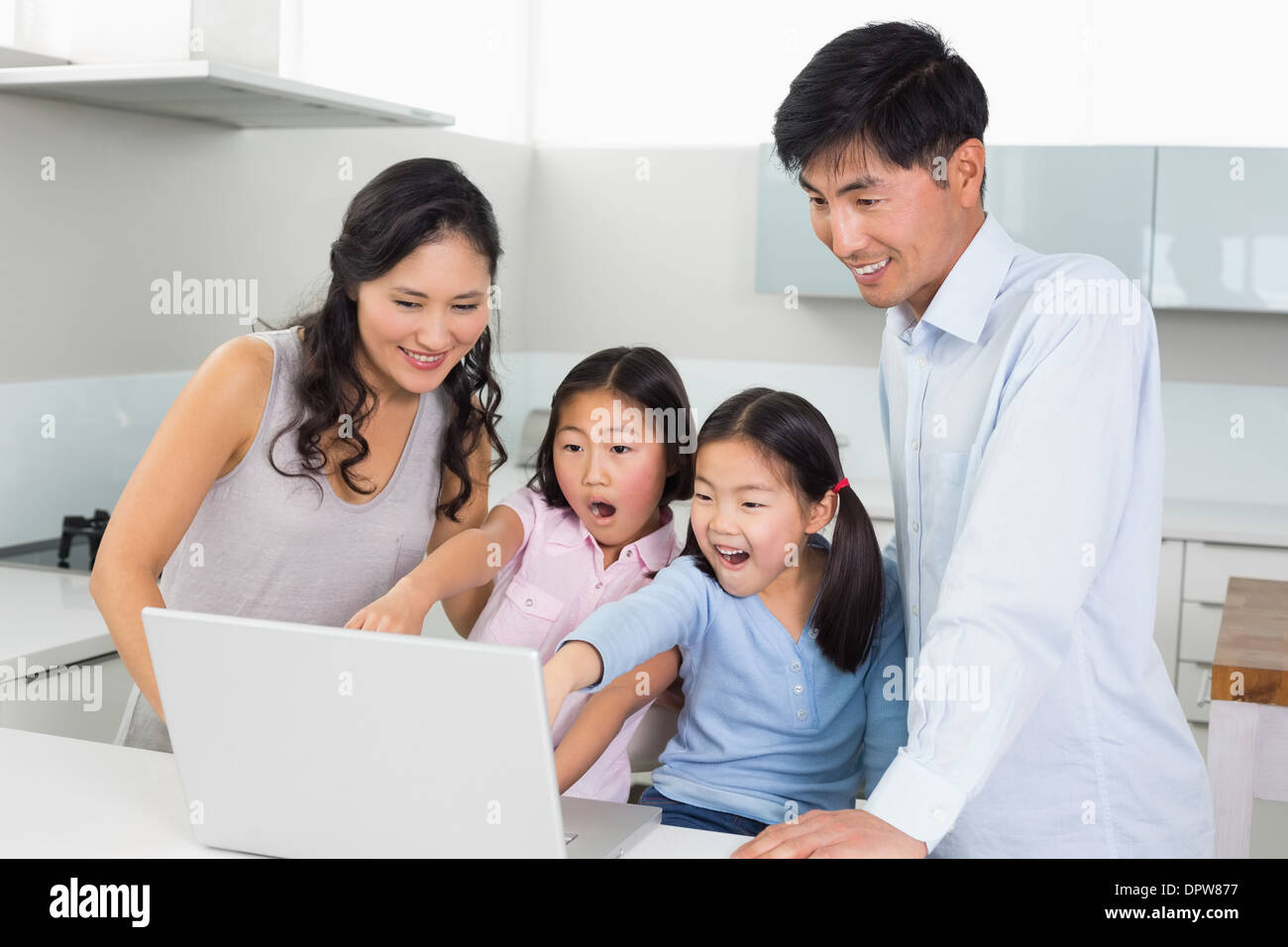 Shocked family of four using laptop in kitchen Stock Photo - Alamy