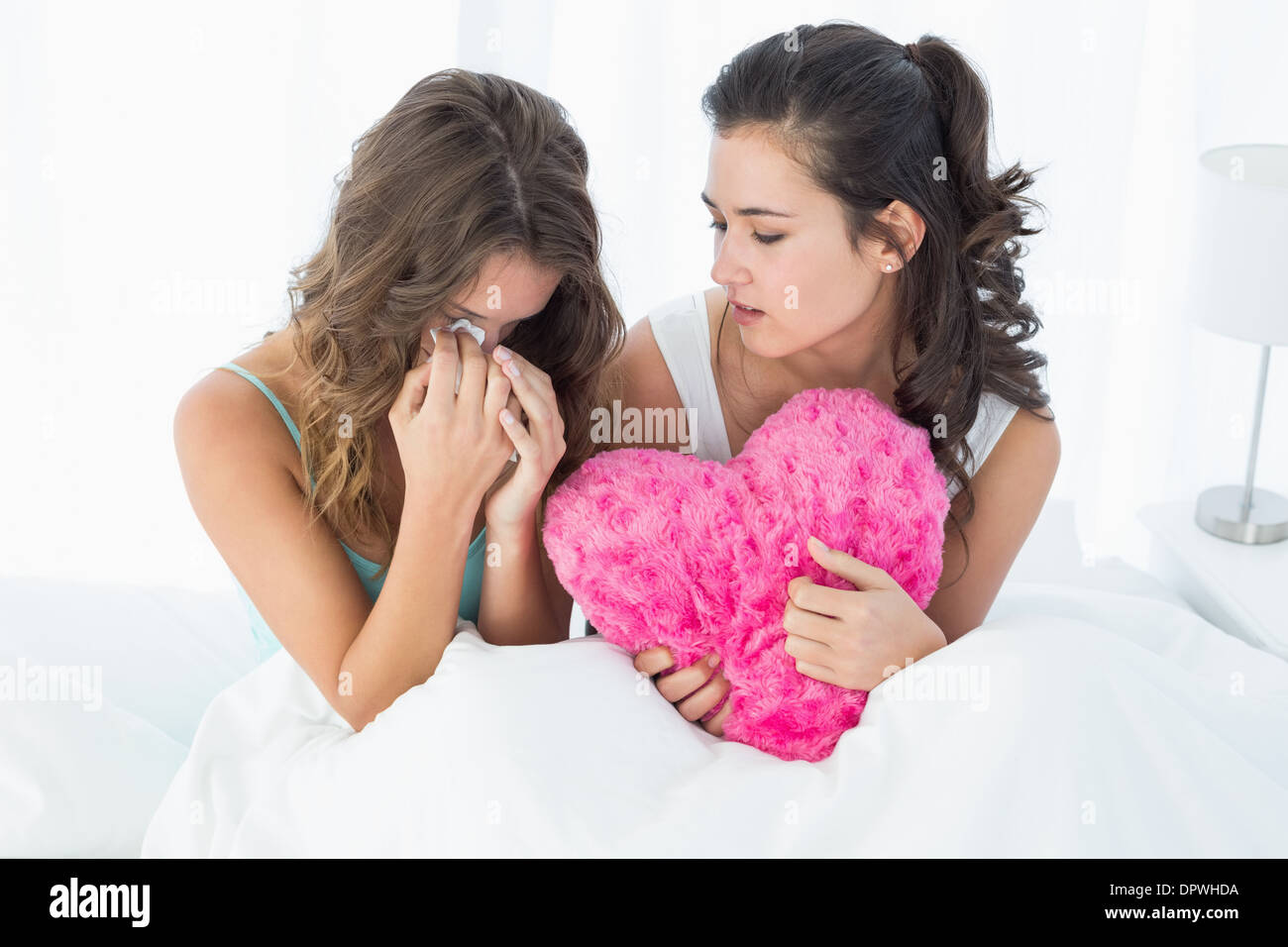 Woman consoling a crying female friend in bed Stock Photo - Alamy