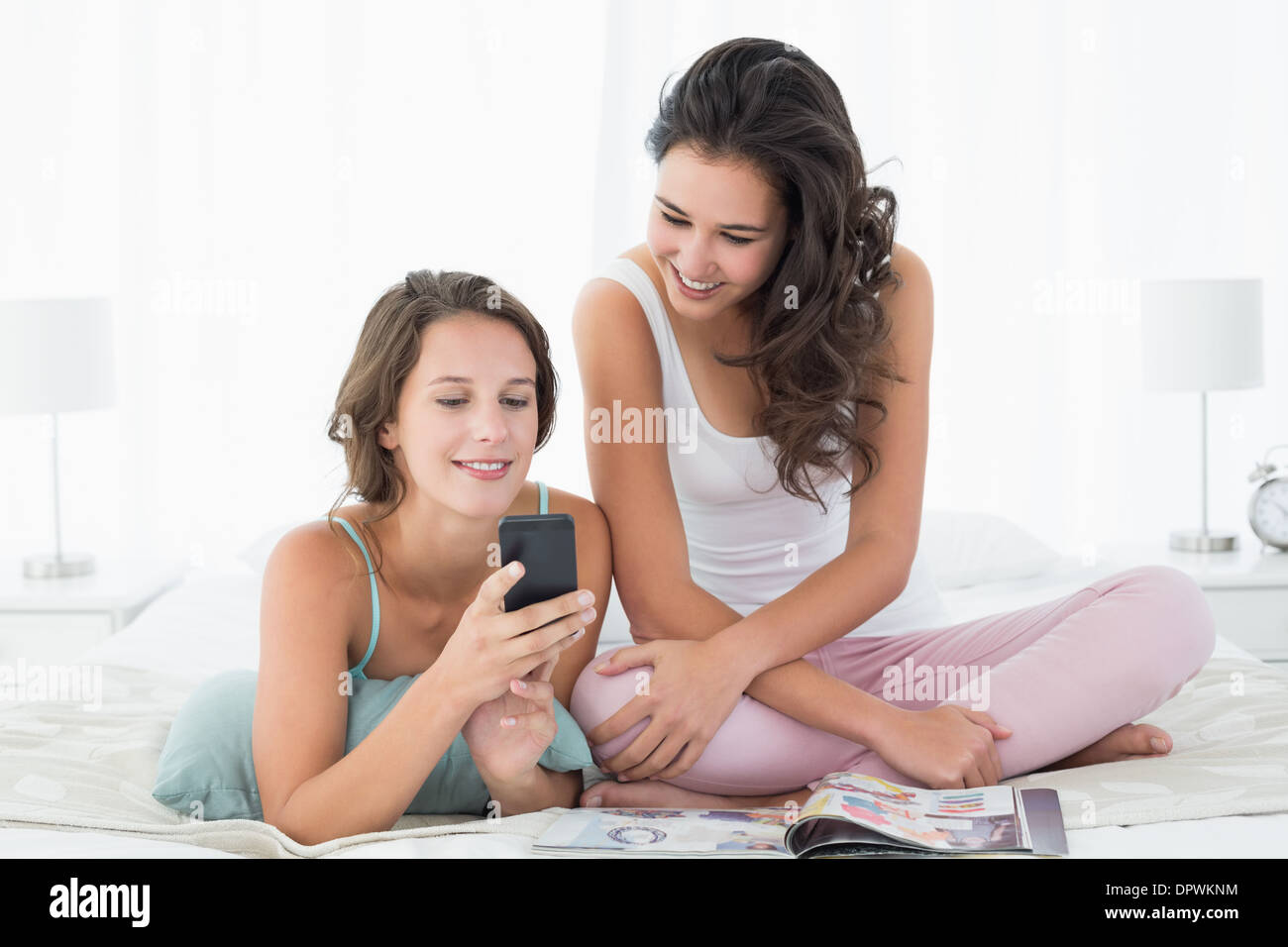 Female friends reading text message in bed Stock Photo - Alamy