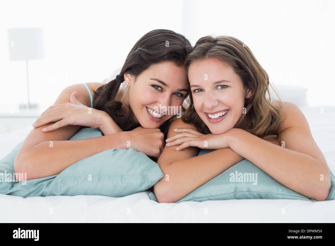 Smiling young female friends lying in bed Stock Photo - Alamy