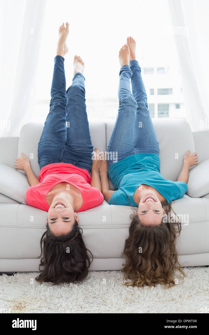 Smiling friends lying on sofa with legs in the air at home Stock Photo ...