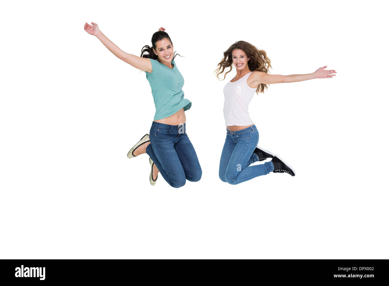 Two cheerful young female friends jumping Stock Photo - Alamy