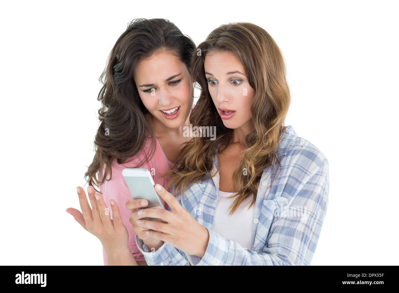 Shocked female friends looking at mobile phone Stock Photo - Alamy