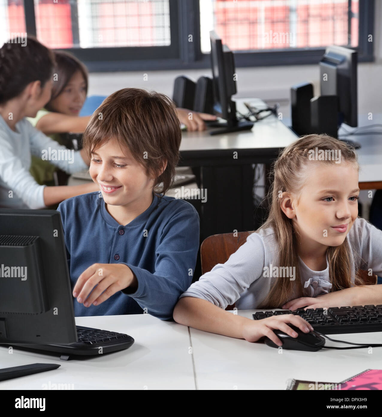 Schoolchildren Using Computer At Desk Stock Photo - Alamy