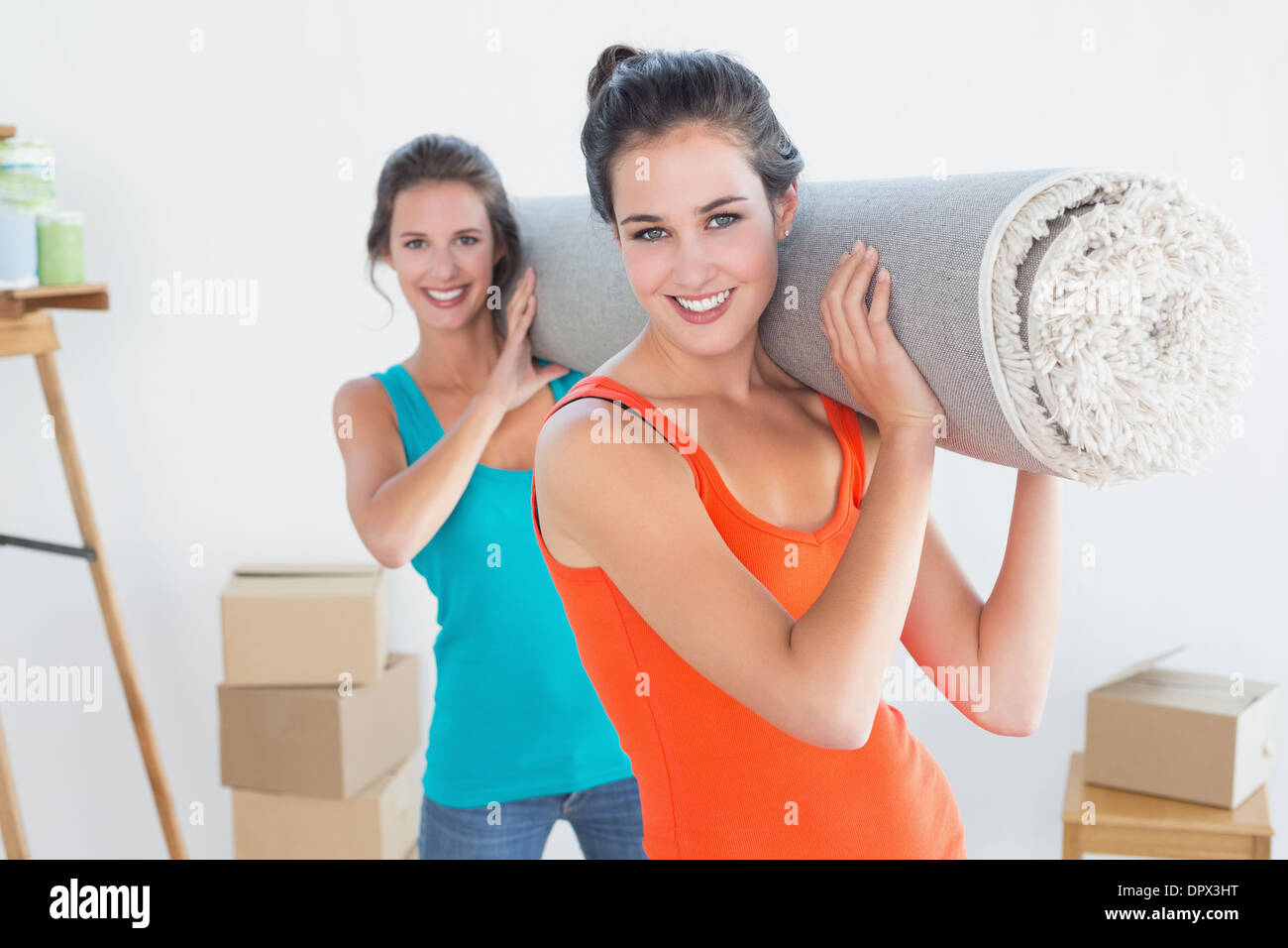Friends carrying rolled rug after moving in a house Stock Photo - Alamy
