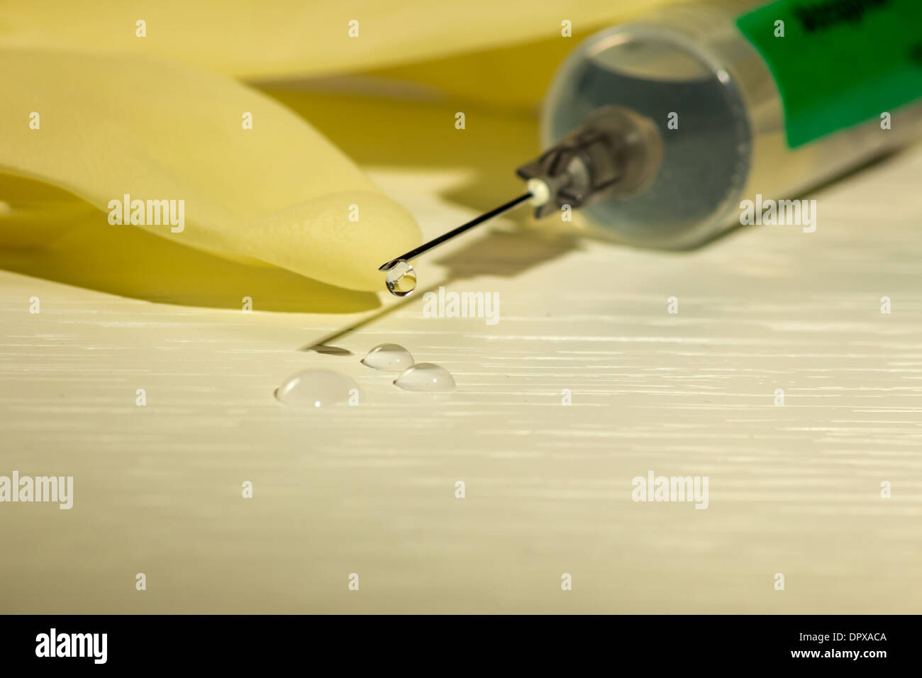 a syringe with a drug dropping from the needle Stock Photo - Alamy