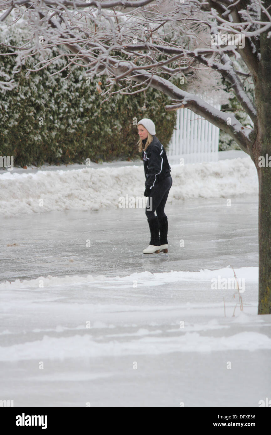 Young girl skating on an ice covered road in a residential area after a ...