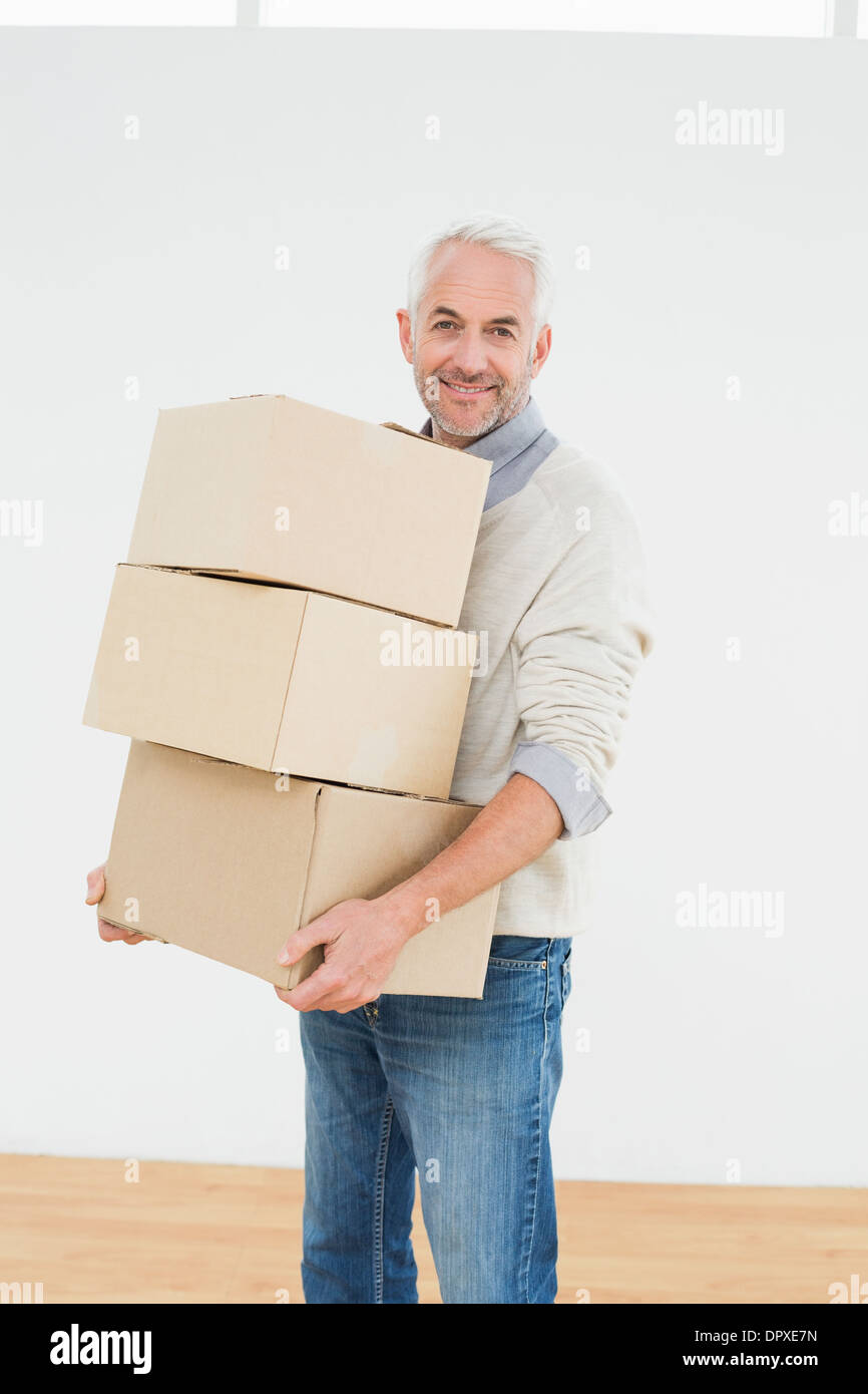 Smiling mature man carrying boxes in a new house Stock Photo - Alamy