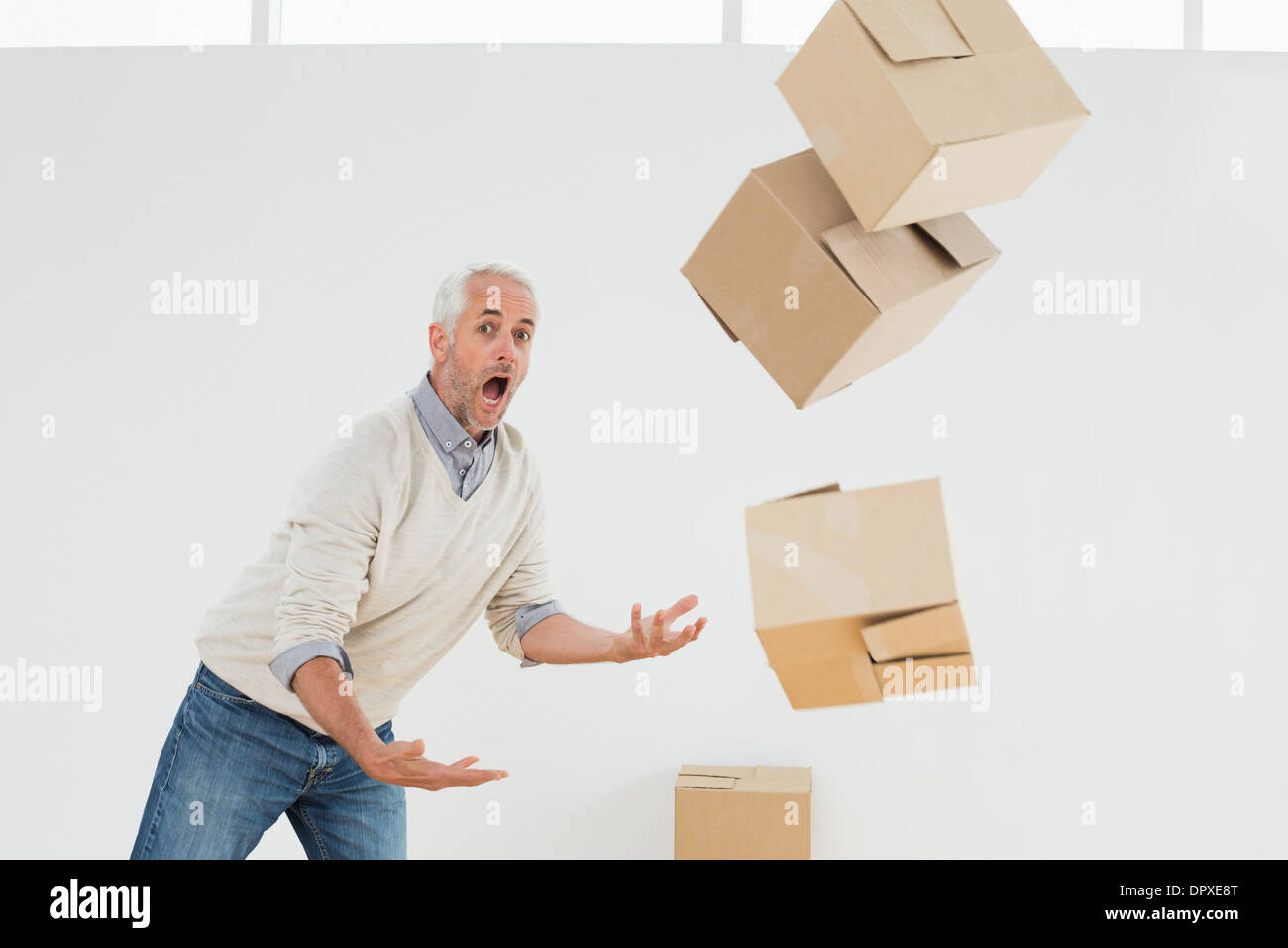 Side view of a mature man with falling boxes Stock Photo - Alamy