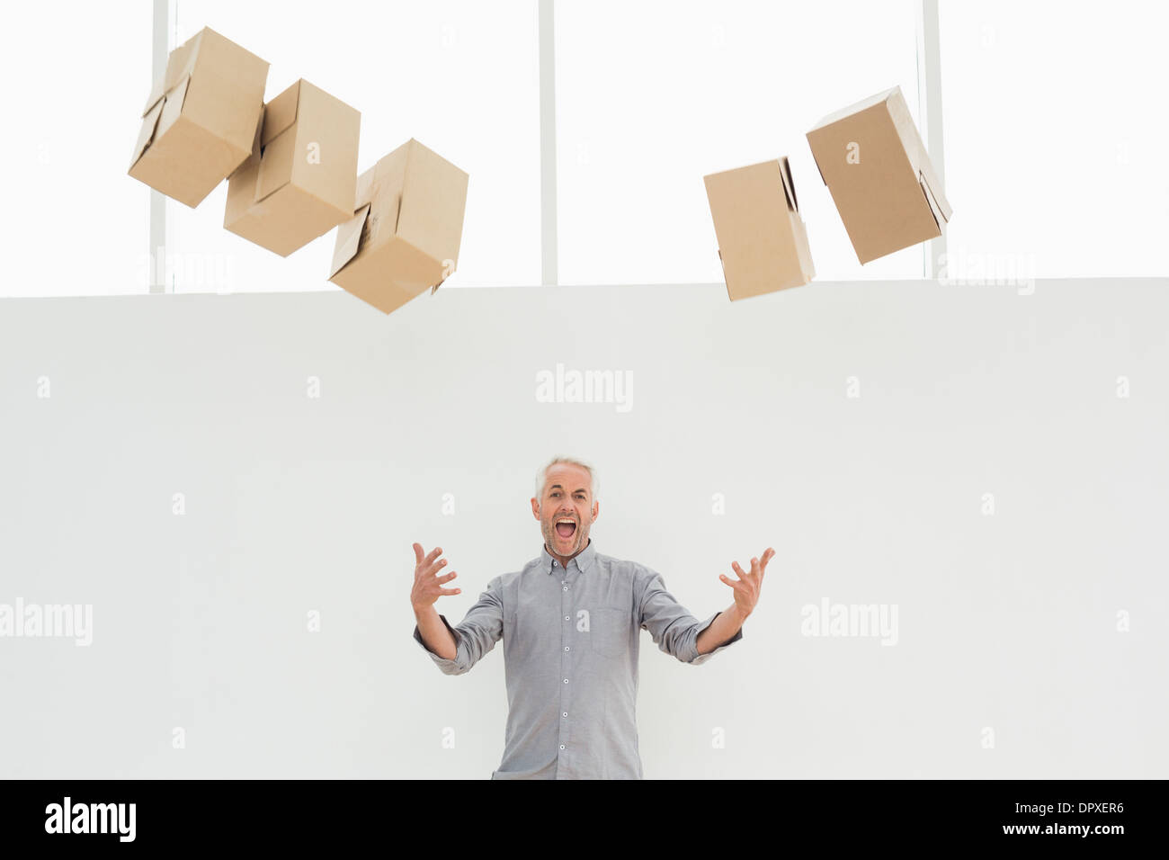 Annoyed mature man with falling boxes Stock Photo - Alamy