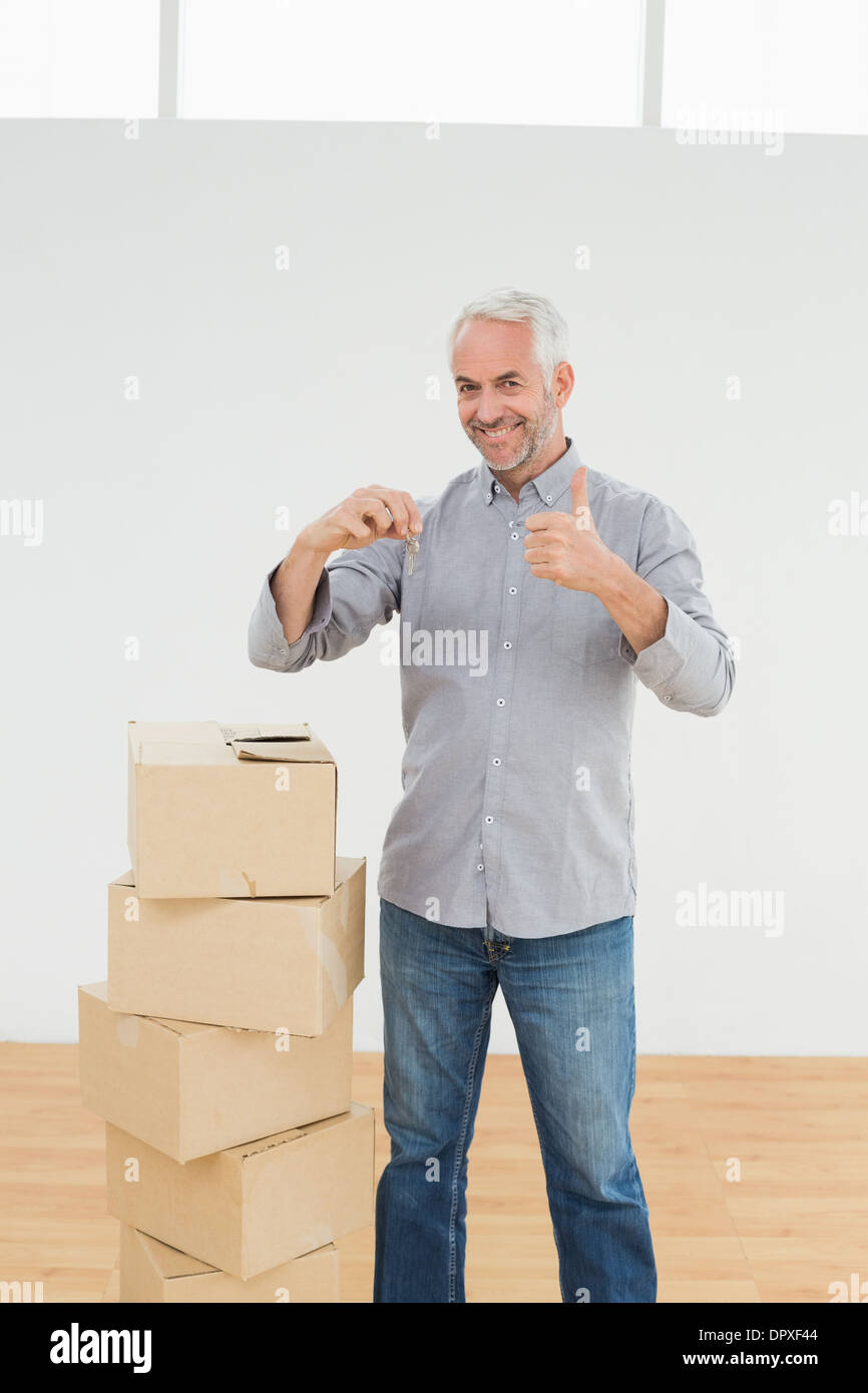 Man with boxes and keys gesturing thumbs up in a new house Stock Photo ...