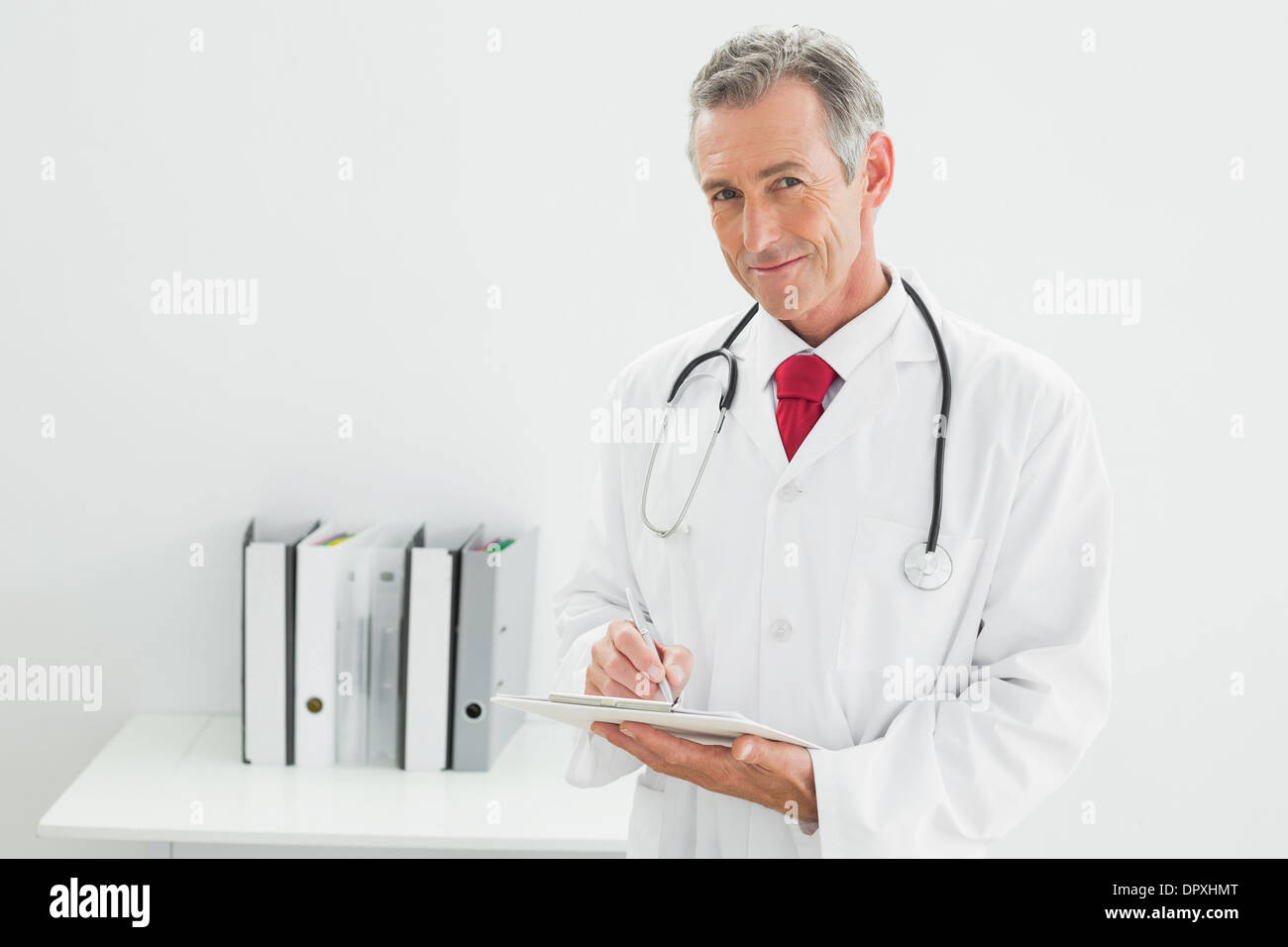 Male doctor writing a report at medical office Stock Photo - Alamy