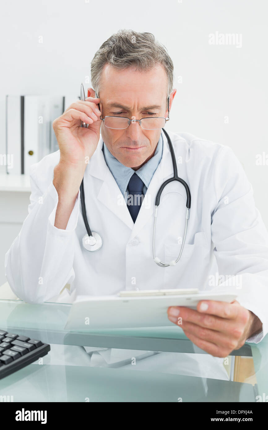 Doctor reading a report at medical office Stock Photo - Alamy