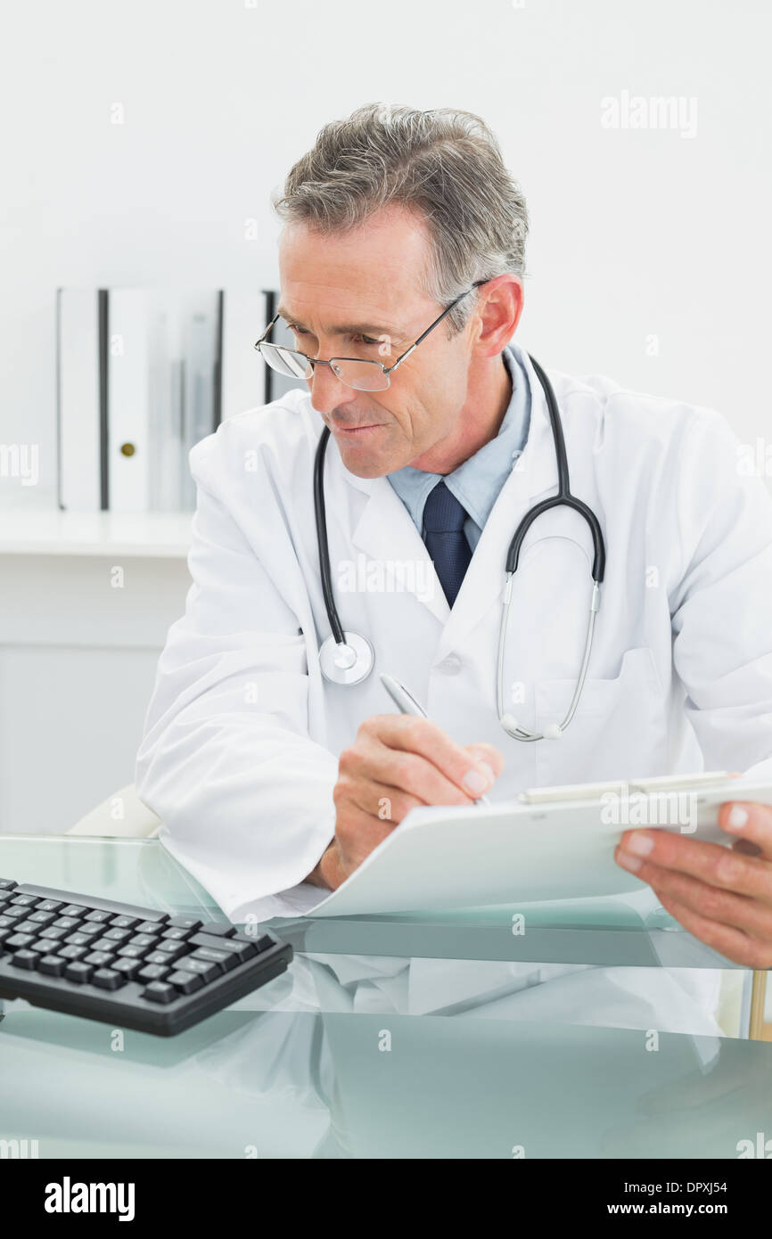 Male doctor writing a report at office Stock Photo - Alamy
