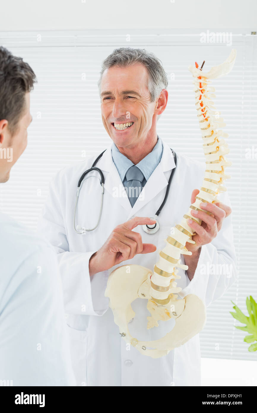 Cheerful doctor explaining spine to patient in office Stock Photo - Alamy