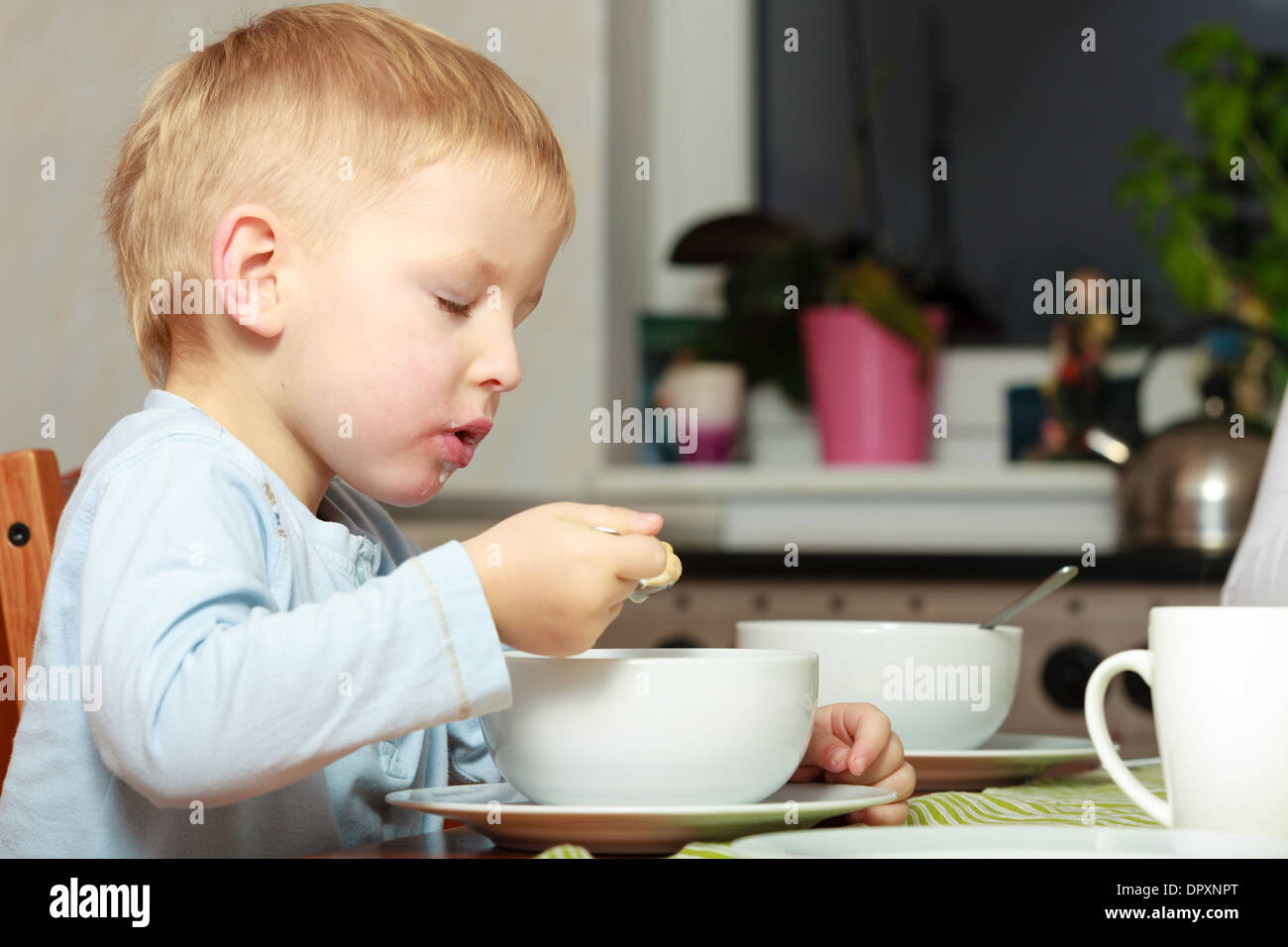 Happy childhood. Blond boy kid child eating corn flakes cereal with ...
