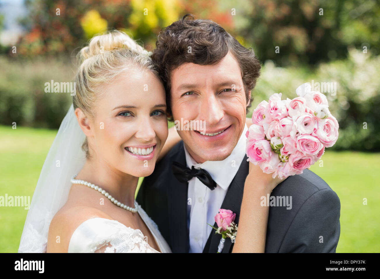 Attractive bride and groom hugging and smiling at camera Stock Photo ...