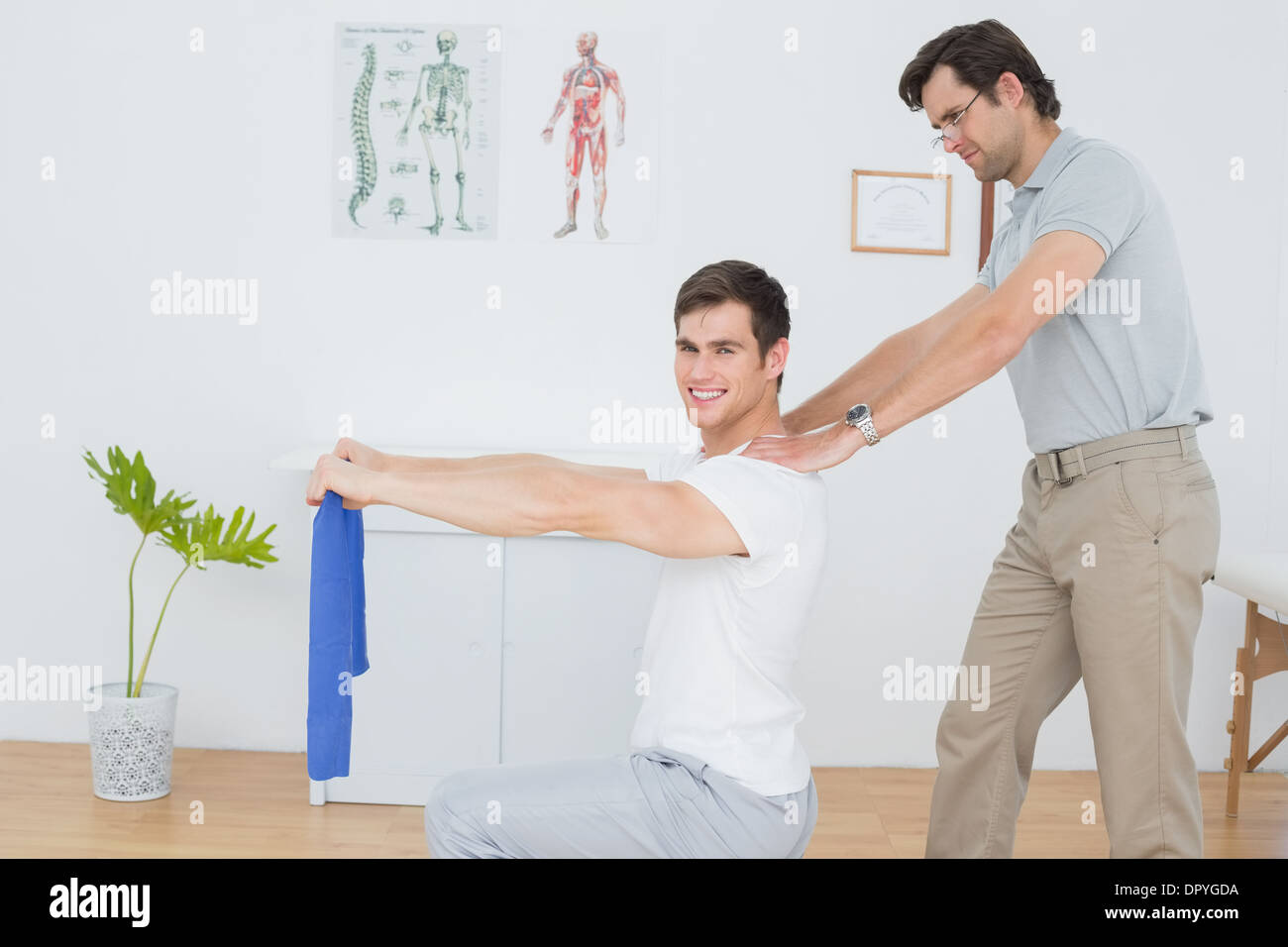 Male therapist assisting young man with exercises Stock Photo - Alamy