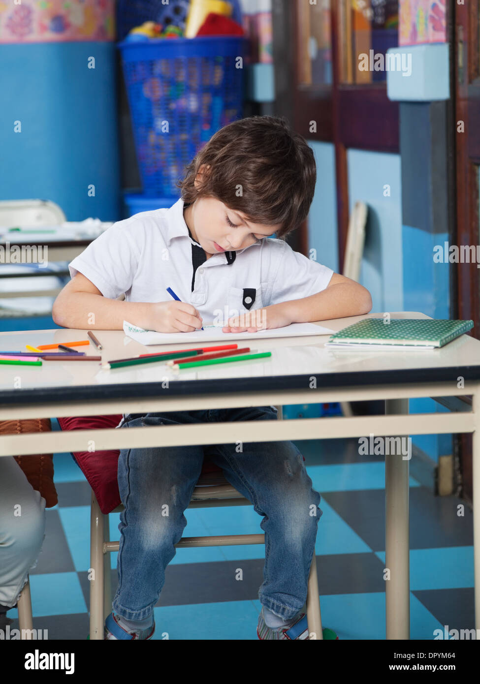 Boy With Color Pencils Drawing In Classroom Stock Photo - Alamy