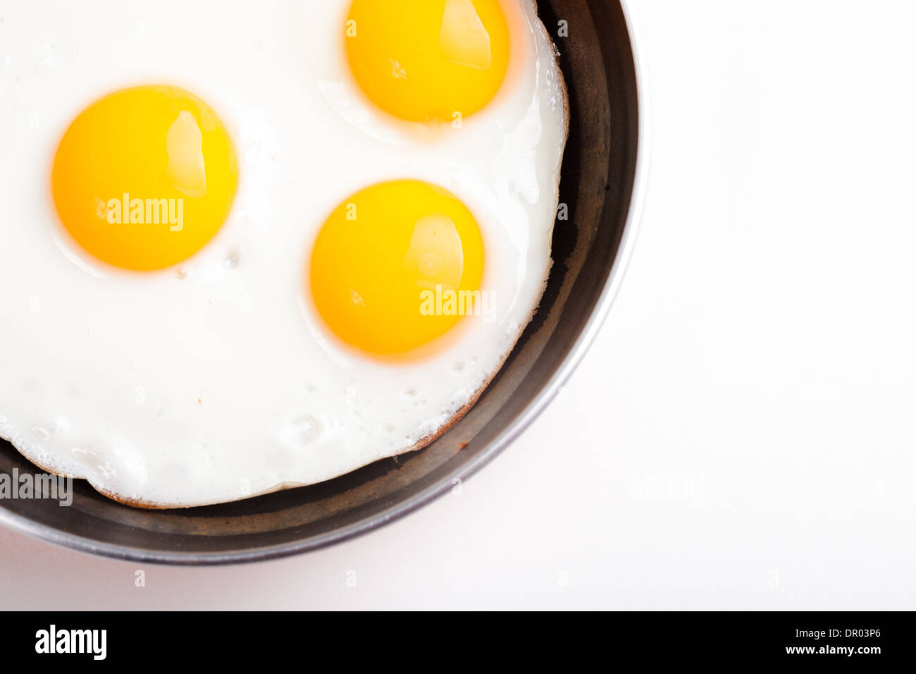 three fried egg on teflon pan without oil isolated on white Stock Photo ...