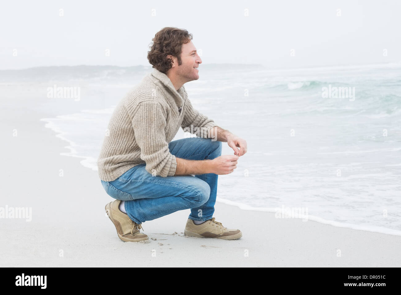 Side view of a casual young man relaxing at beach Stock Photo - Alamy