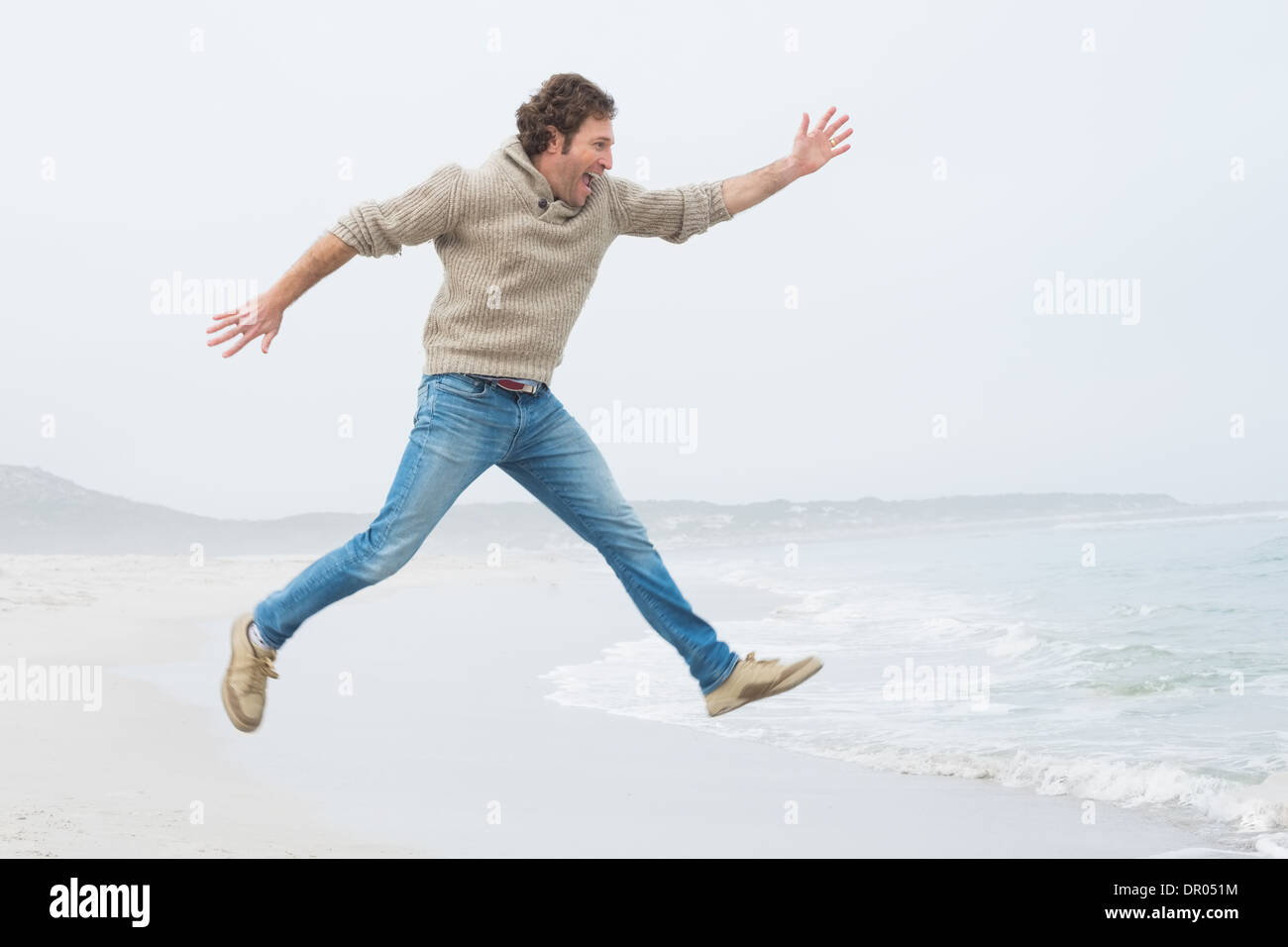 Side view of a casual man jumping at beach Stock Photo - Alamy