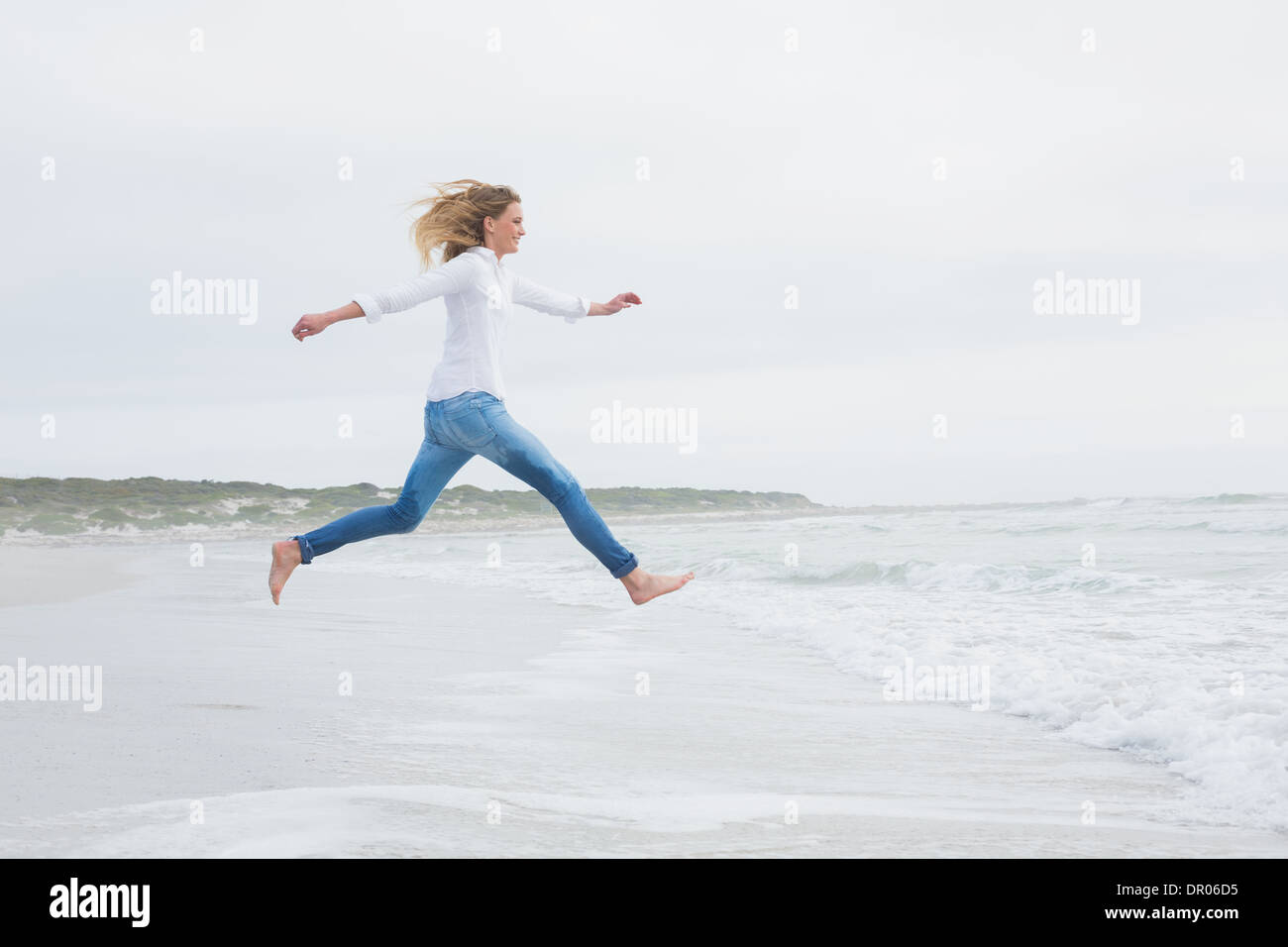 Side view of a casual woman jumping at beach Stock Photo - Alamy