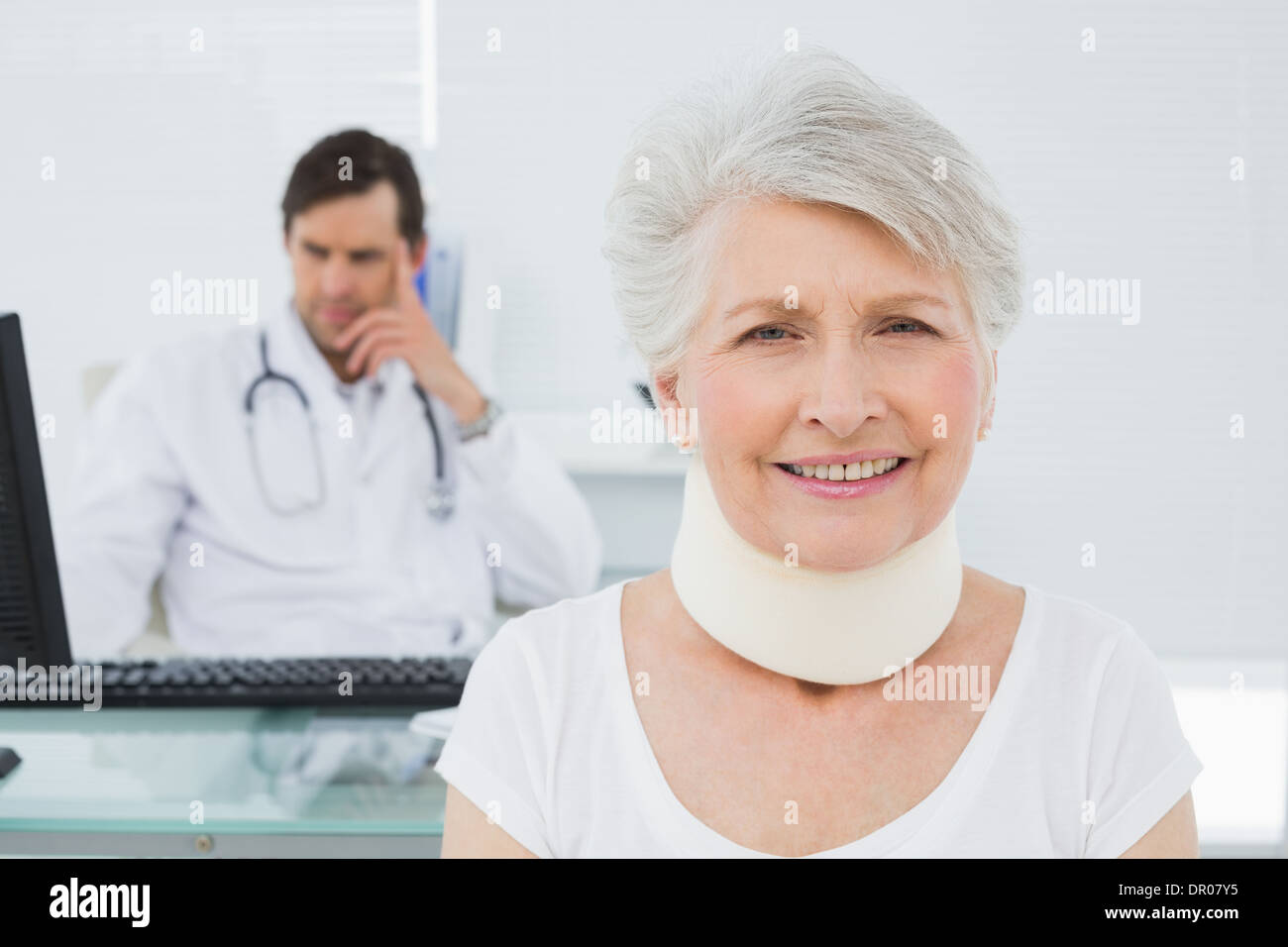 Senior patient in surgical collar with doctor at office Stock Photo - Alamy