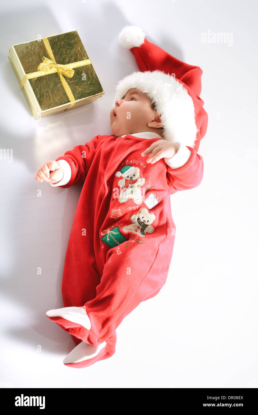 Cute baby in santa wear and gold gift on white Stock Photo - Alamy