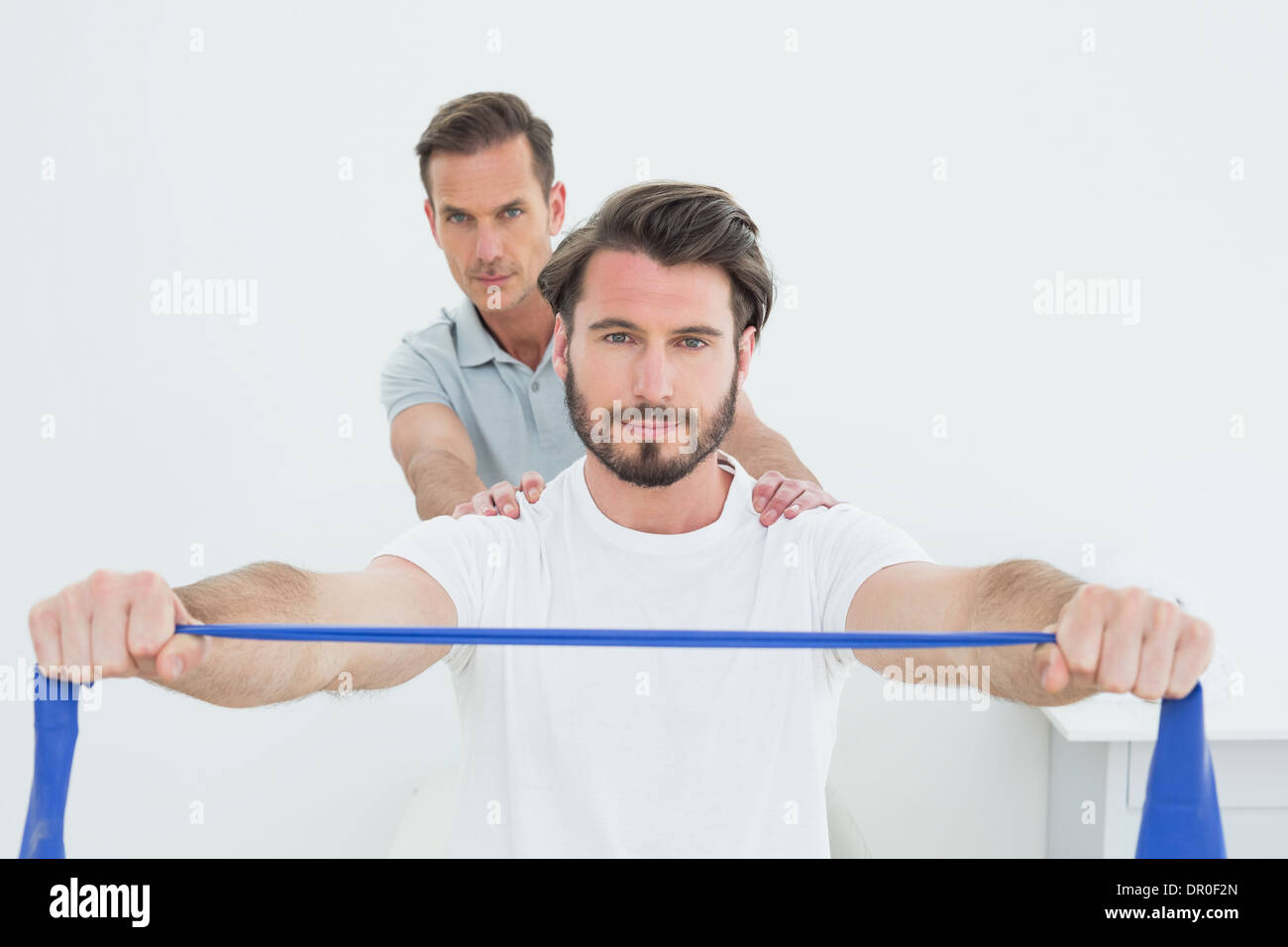 Male therapist assisting a young man with exercises Stock Photo - Alamy