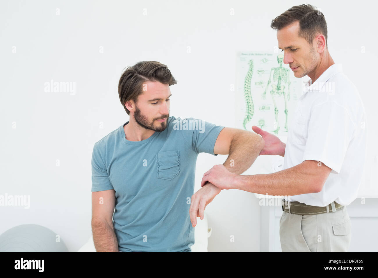 Male physiotherapist examining a young man's arm Stock Photo - Alamy