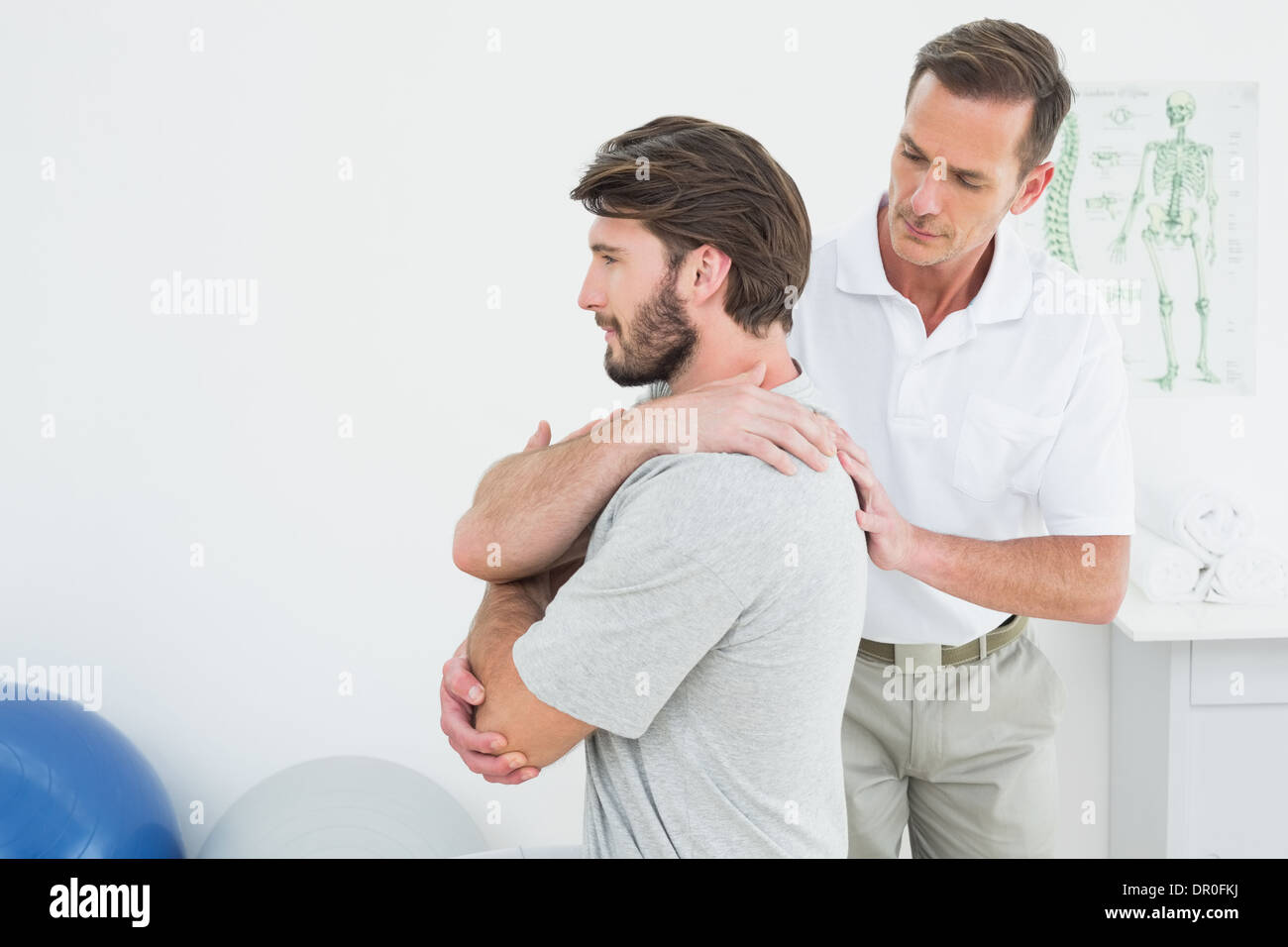 Male physiotherapist examining a young man Stock Photo - Alamy