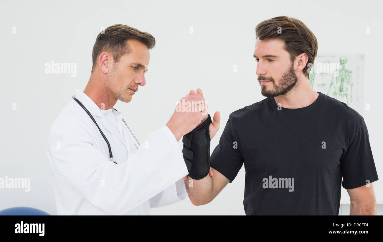Male physiotherapist examining a man's wrist Stock Photo - Alamy