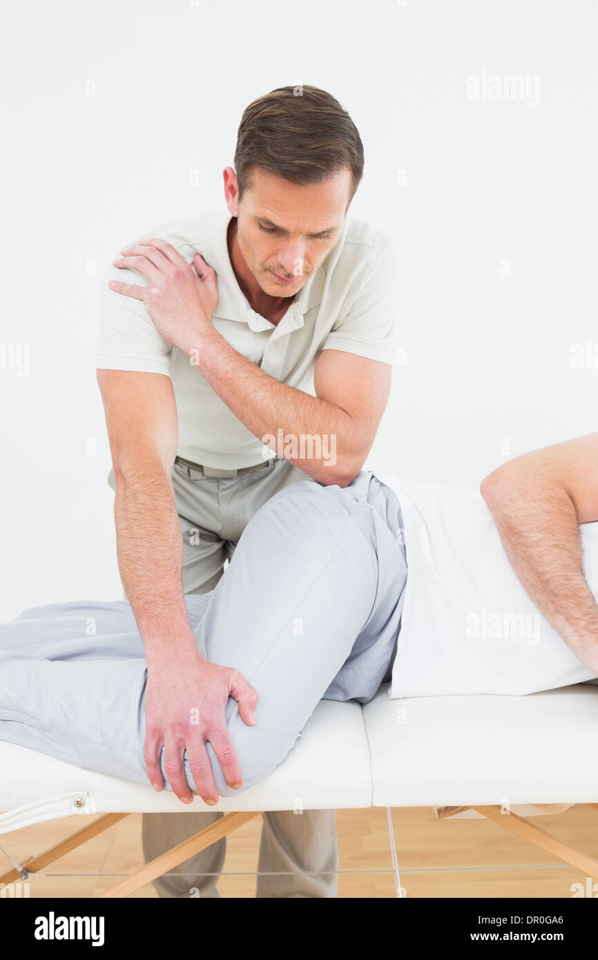 Male physiotherapist examining a young man Stock Photo - Alamy