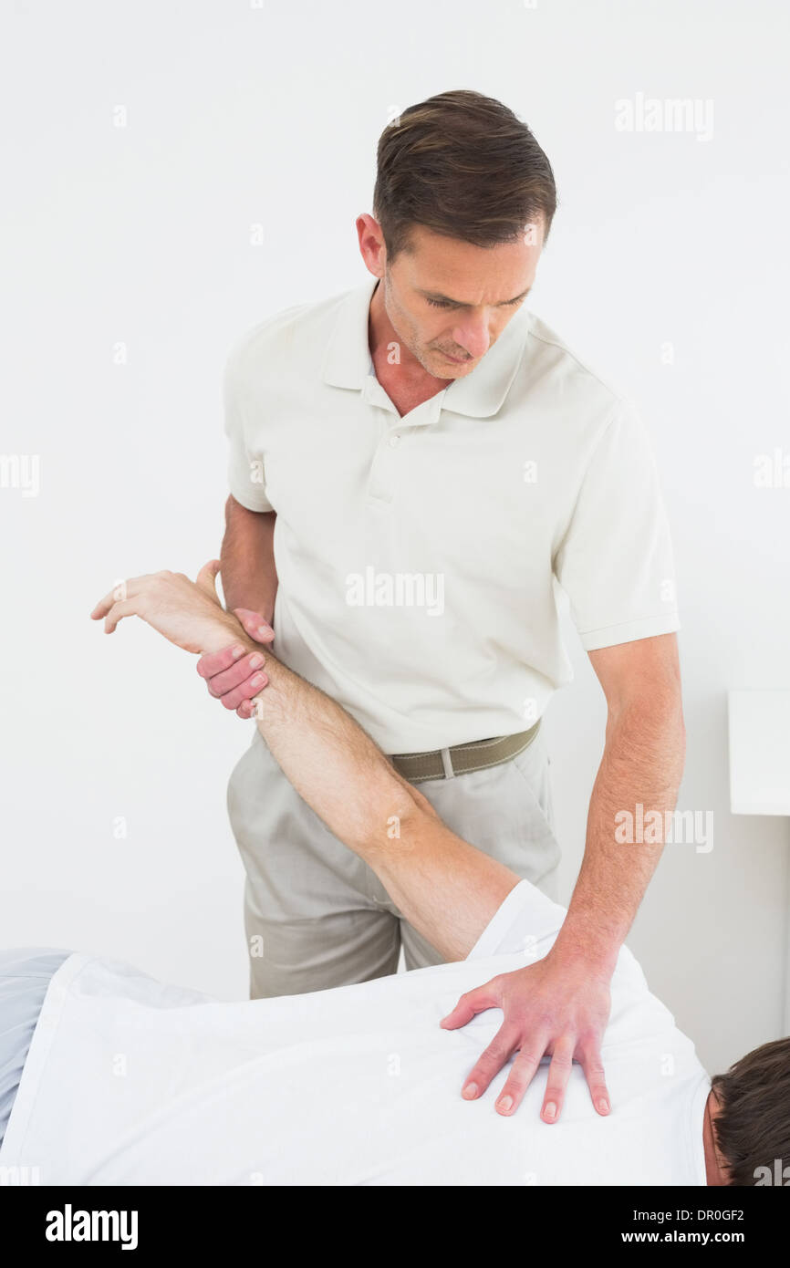 Male physiotherapist stretching a man's hand Stock Photo - Alamy