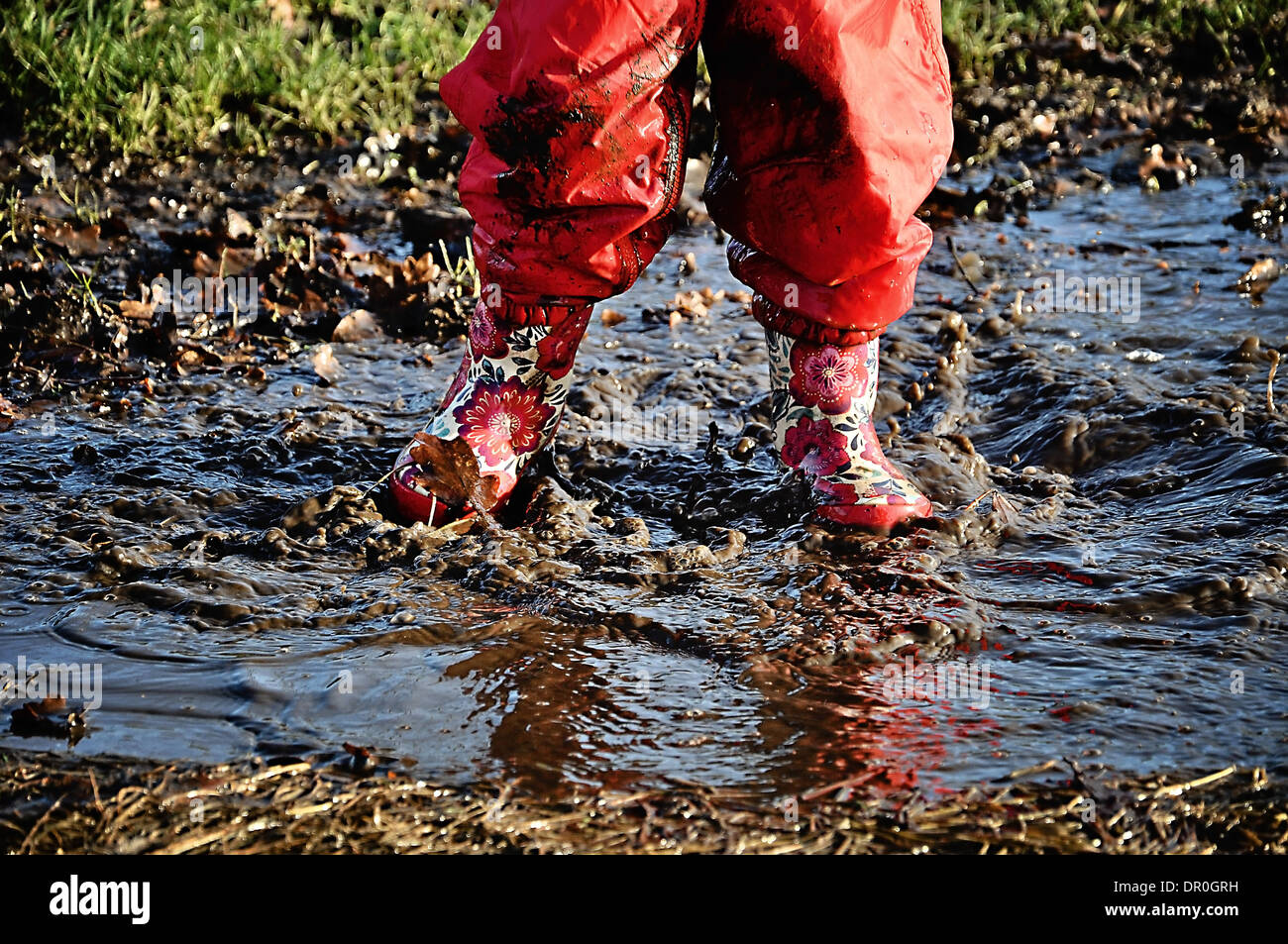 Child in wellington boots splashing in a puddle Stock Photo - Alamy