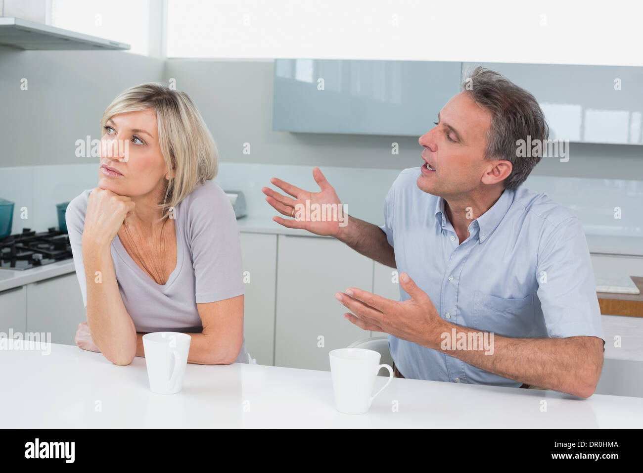 Couple with coffee cups having a fight in kitchen Stock Photo - Alamy